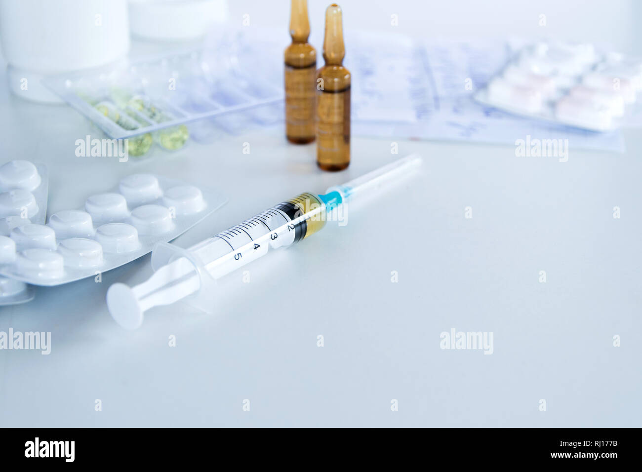 Medical syringe with injection solution, medicine pills and capsules on ...