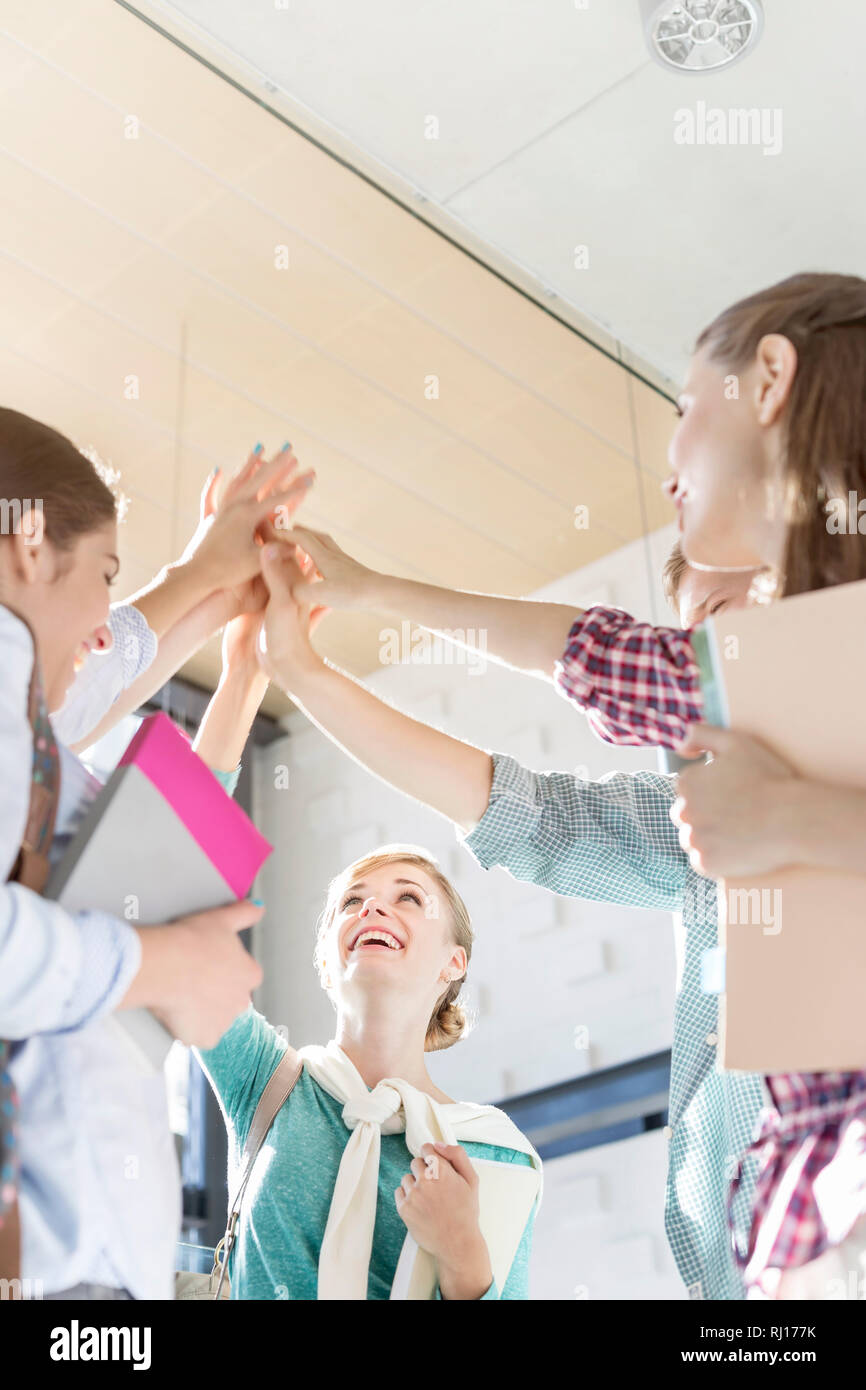 Students stacking hands in university corridor Stock Photo - Alamy