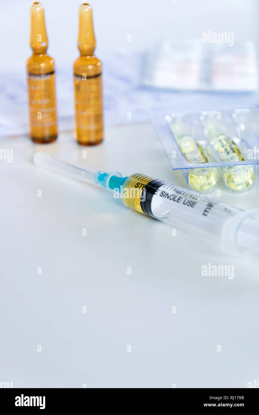 Medical syringe with injection solution, medicine pills and capsules on ...