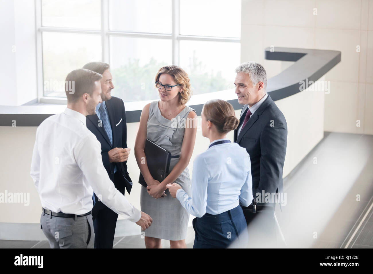 Business colleagues talking while standing at reception lobby in office ...