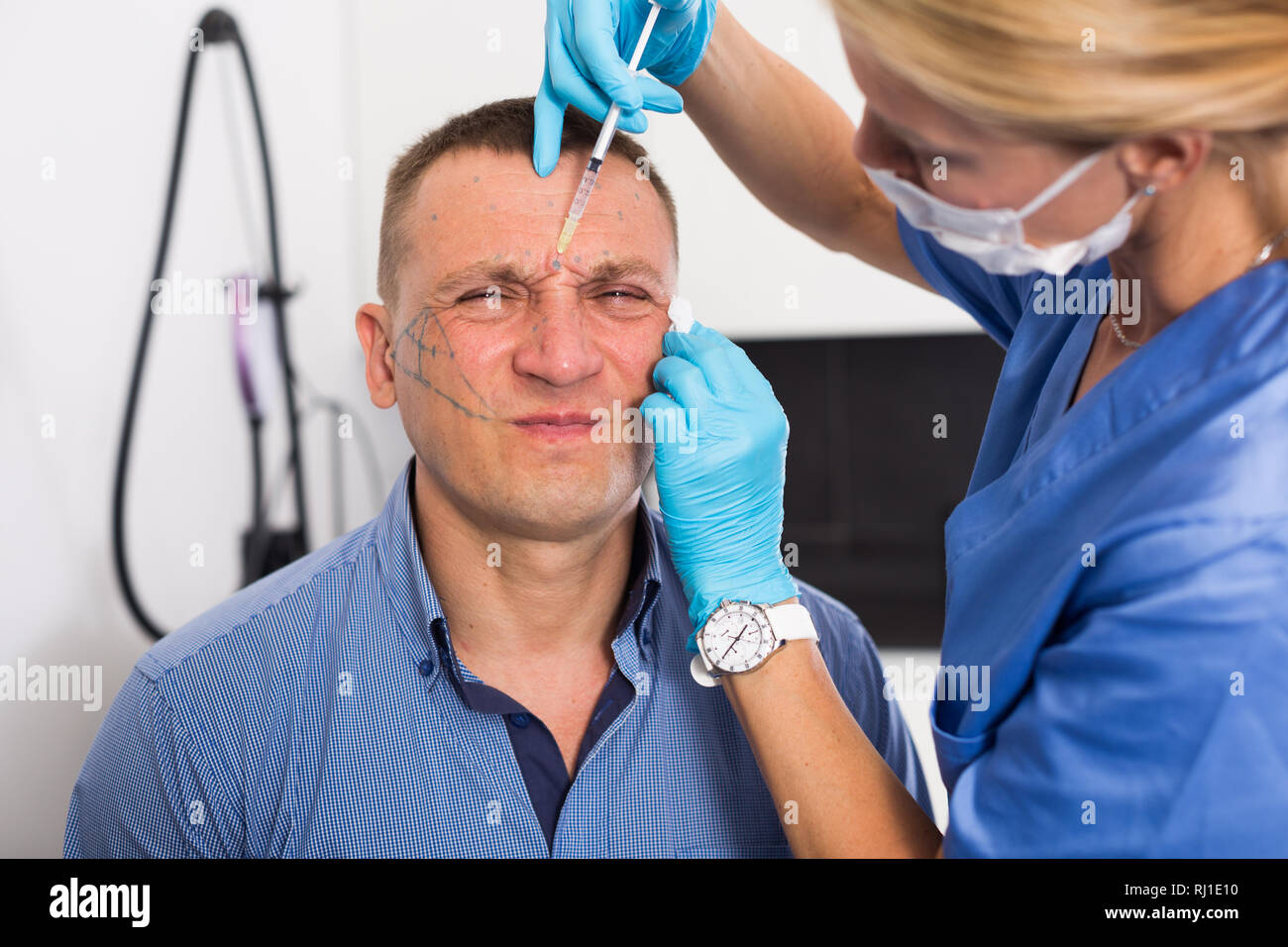 Female doctor is doing injection to patient in skin of face in estetic ...