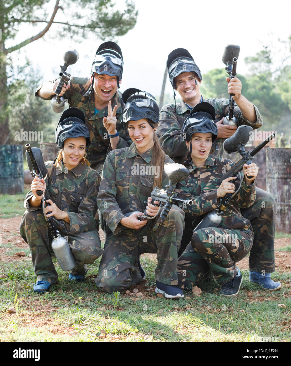 Group of happy paintball players in camouflage standing with guns on ...