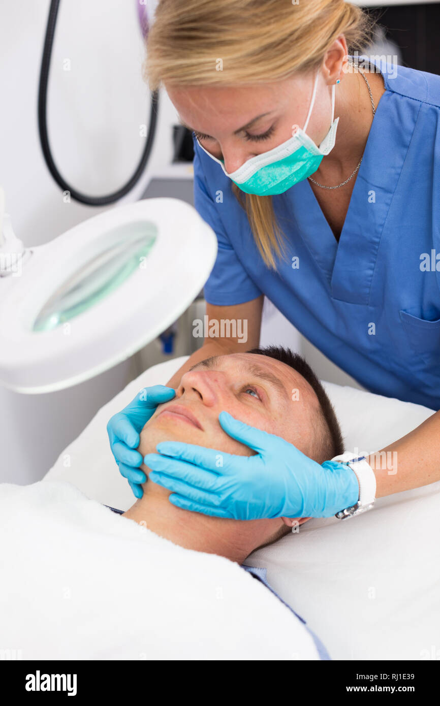 Woman doctor is massaging face of patient after the procedure in ...