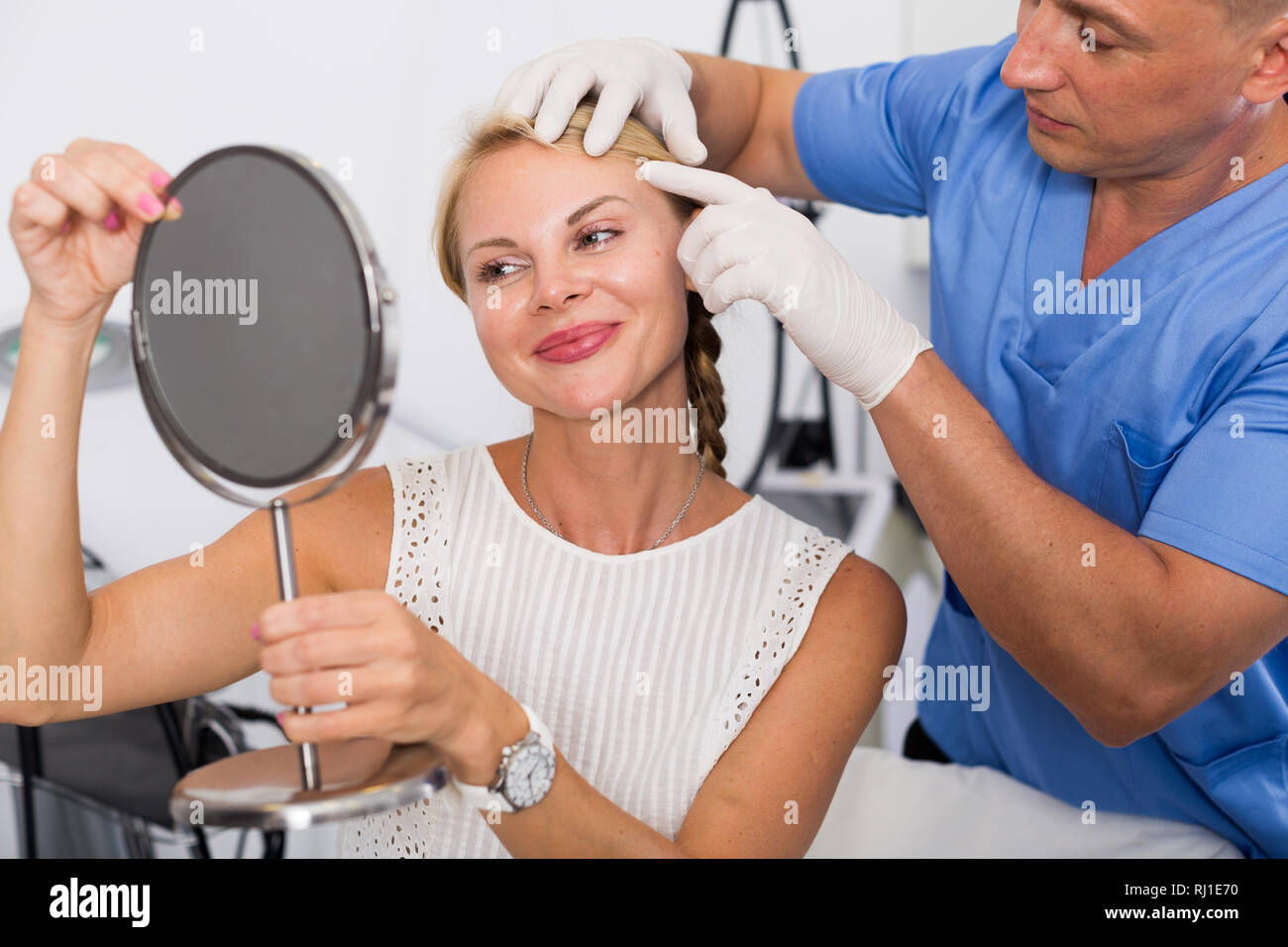 Doctor is examining woman patient behind mirror before the procedure in ...