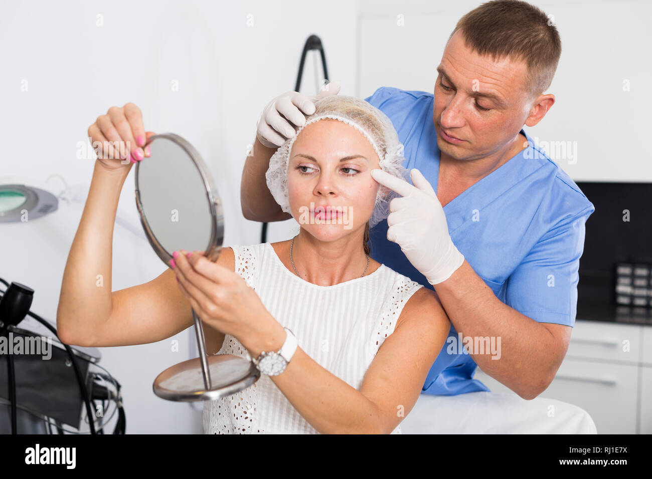 Doctor is examining woman patient behind mirror before the procedure in ...