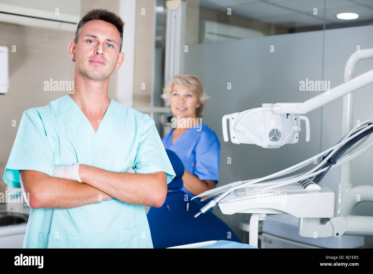 Portrait of professional male dentist with arms crossed with dental ...