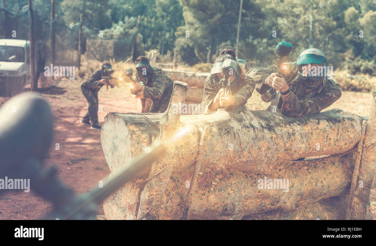 Portrait of team of positive smiling adult people playing on paintball ...