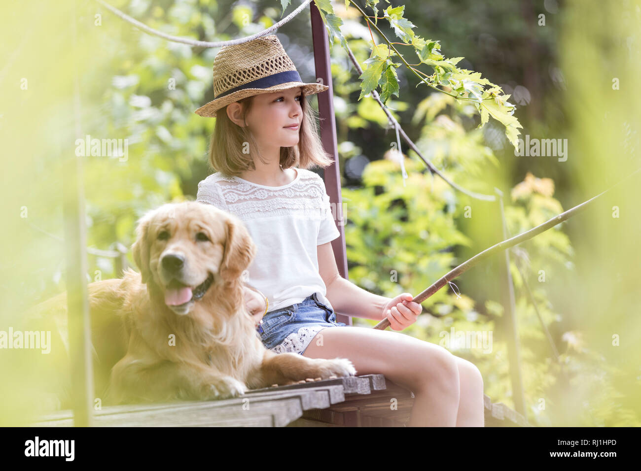 Girl fishing while sitting with dog on pier Stock Photo - Alamy