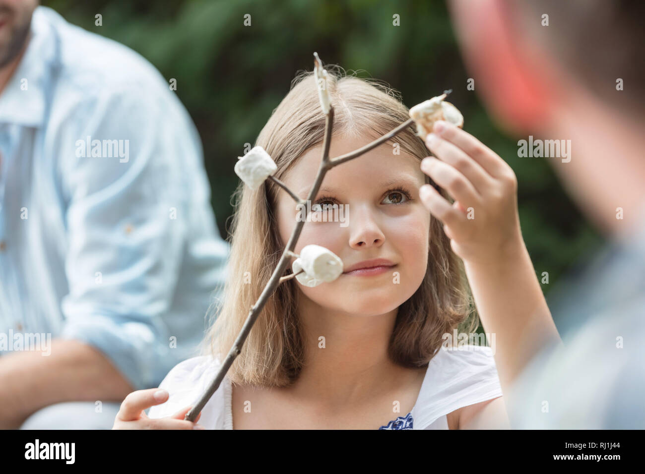 Cute girl holding stick with marshmallows at park Stock Photo - Alamy