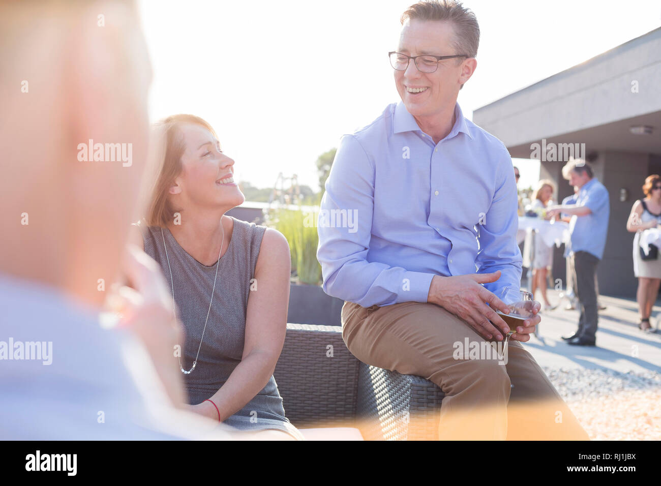 Business colleagues sitting while talking during party on rooftop Stock ...