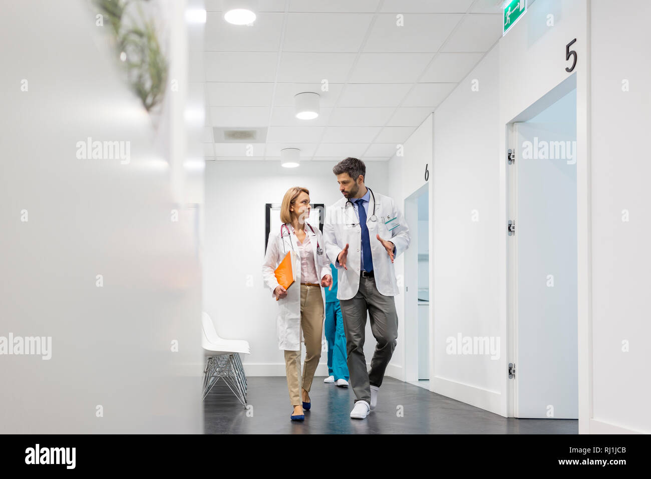 Colleagues discussing while talking in corridor at hospital Stock Photo ...