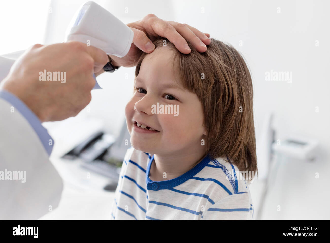 Cropped image of doctor measuring temperature of boy with infrared ...