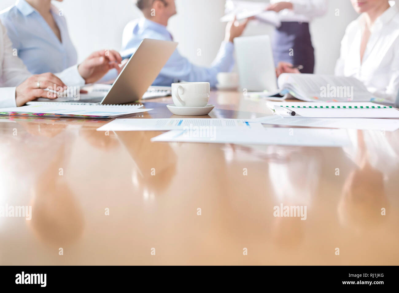 Documents on table amidst colleagues in boardroom at office Stock Photo ...