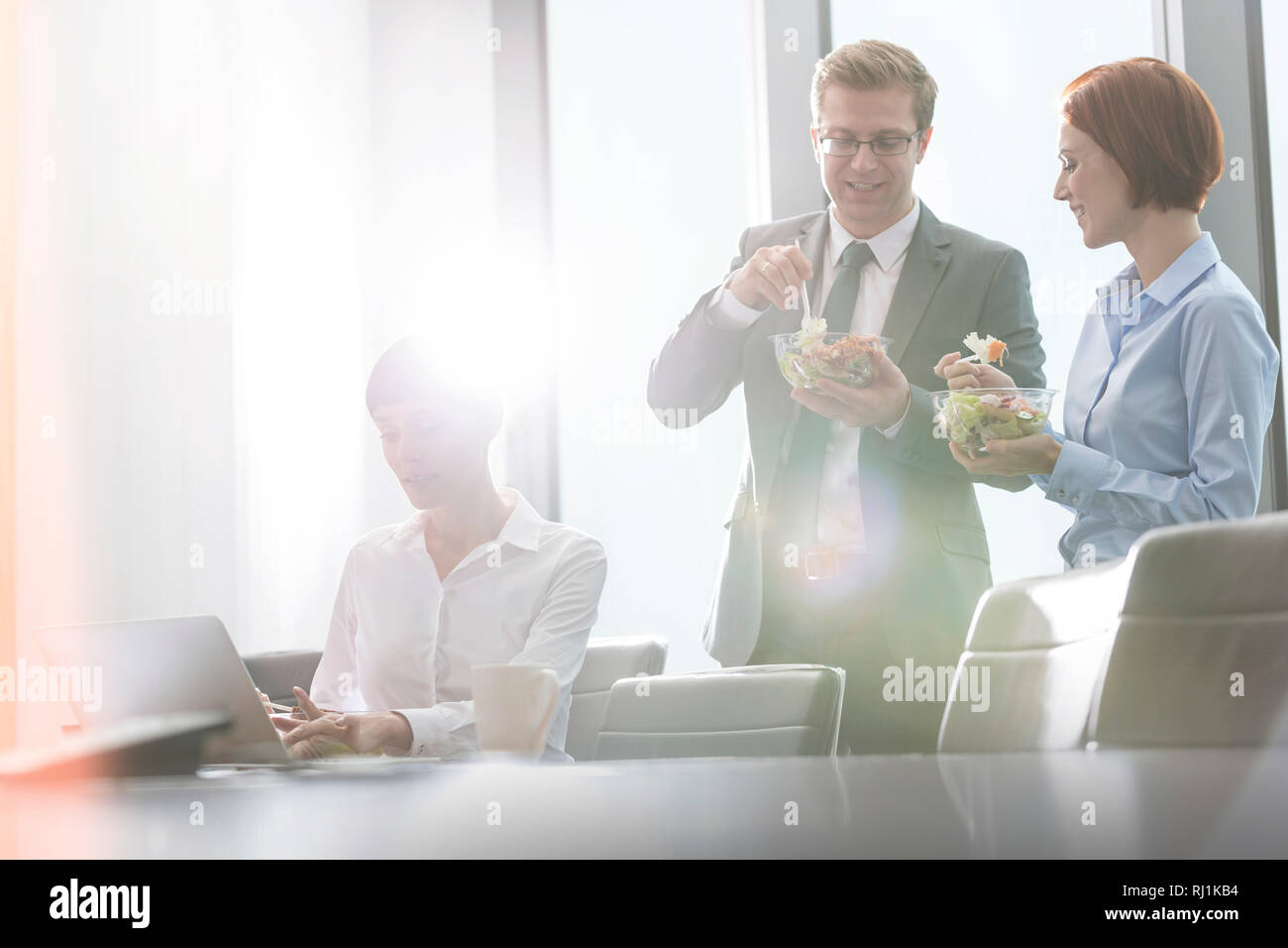Business colleagues eating lunch in boardroom during meeting at office ...