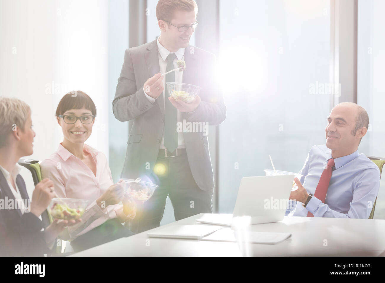 Business colleagues eating lunch in boardroom during meeting at office ...