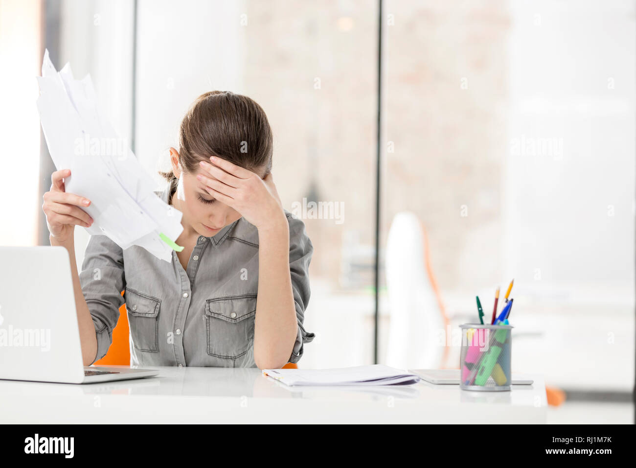 Overworked businesswoman holding documents while suffering from ...