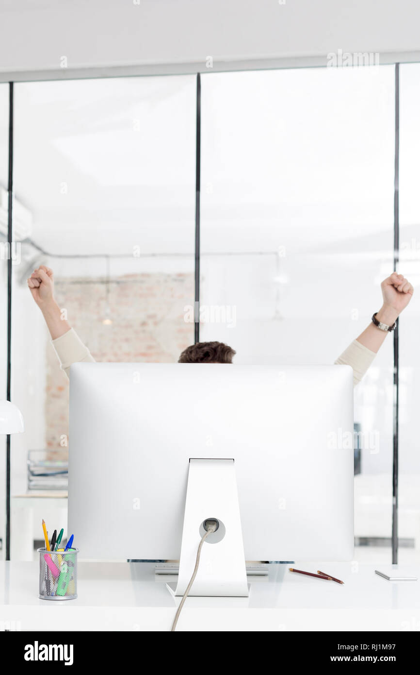 Businessman celebrating success while raising hands at computer desk ...