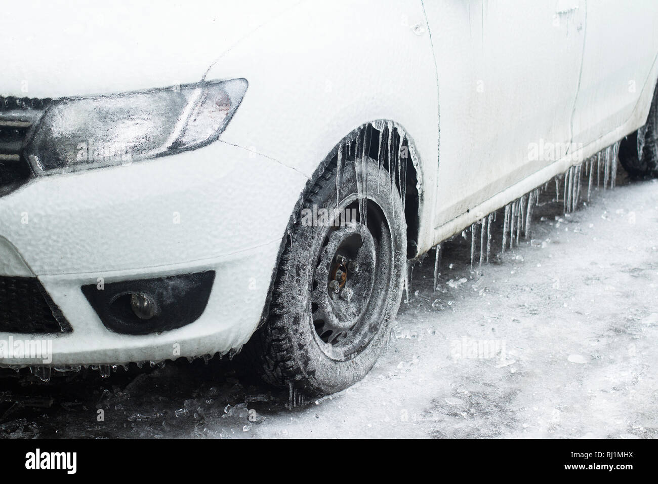 side view closeup of white frozen car with freezing rain icicles ...