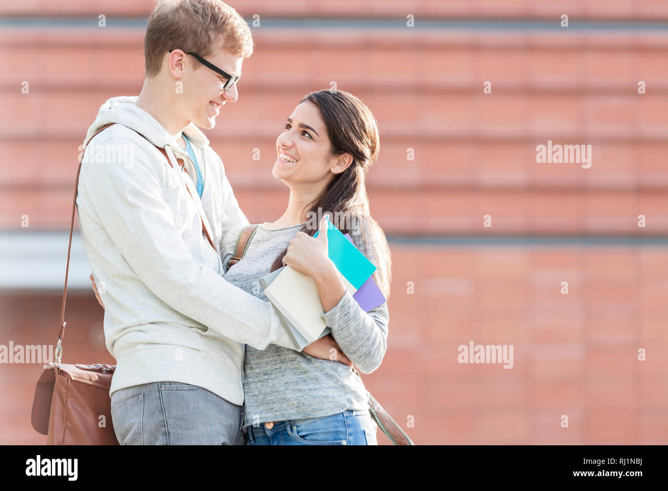 Young couple with books standing at university Stock Photo - Alamy