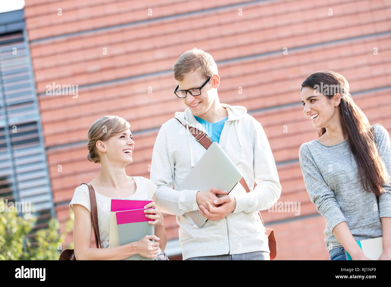 Happy friends with books talking in university campus Stock Photo - Alamy