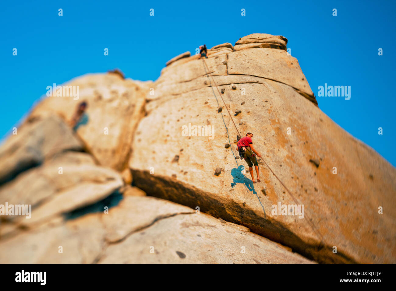 Low-angle view of two rock climbers climbing on mountain top Stock ...