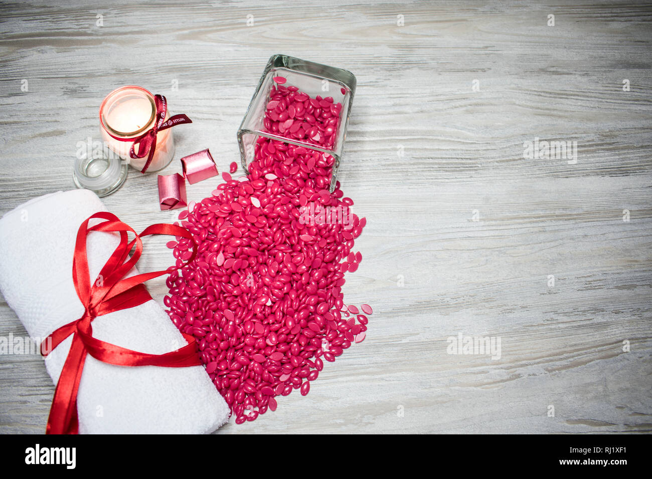 on the table is a red granulated wax, candy, a white towel and a ...