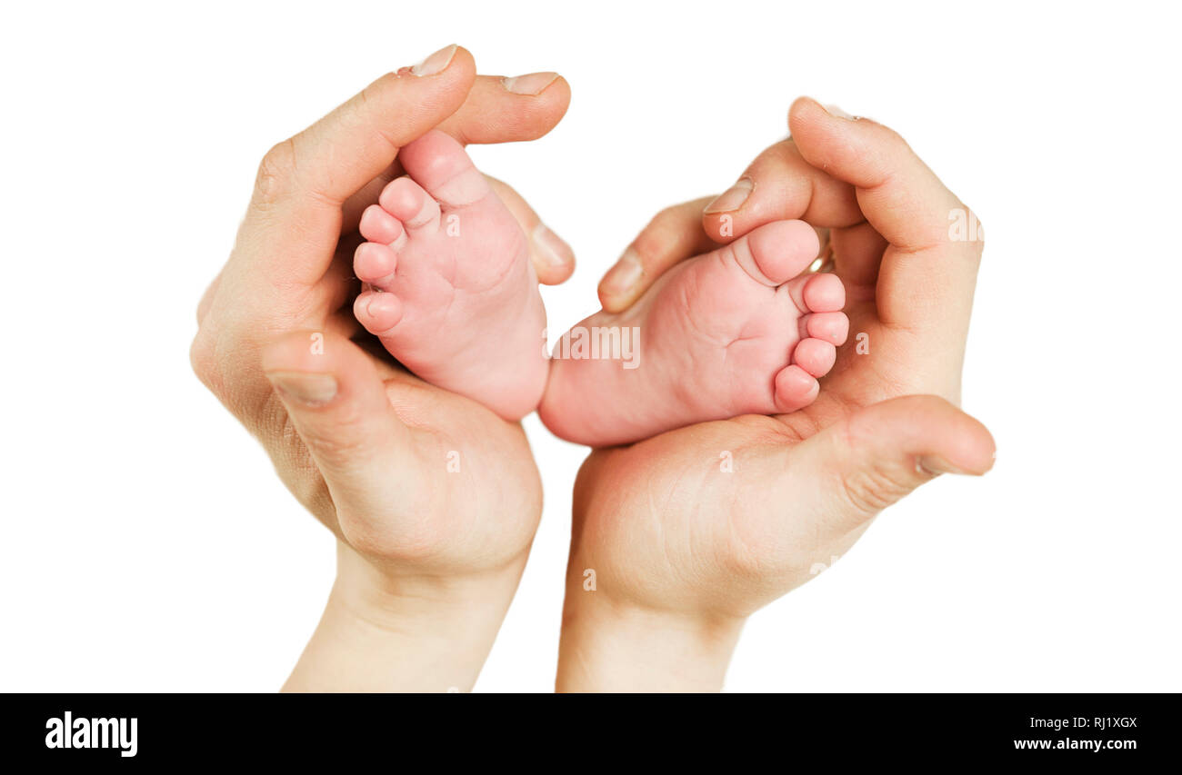Close-up mother hand holding newborn baby feet in hear shape. Macro ...