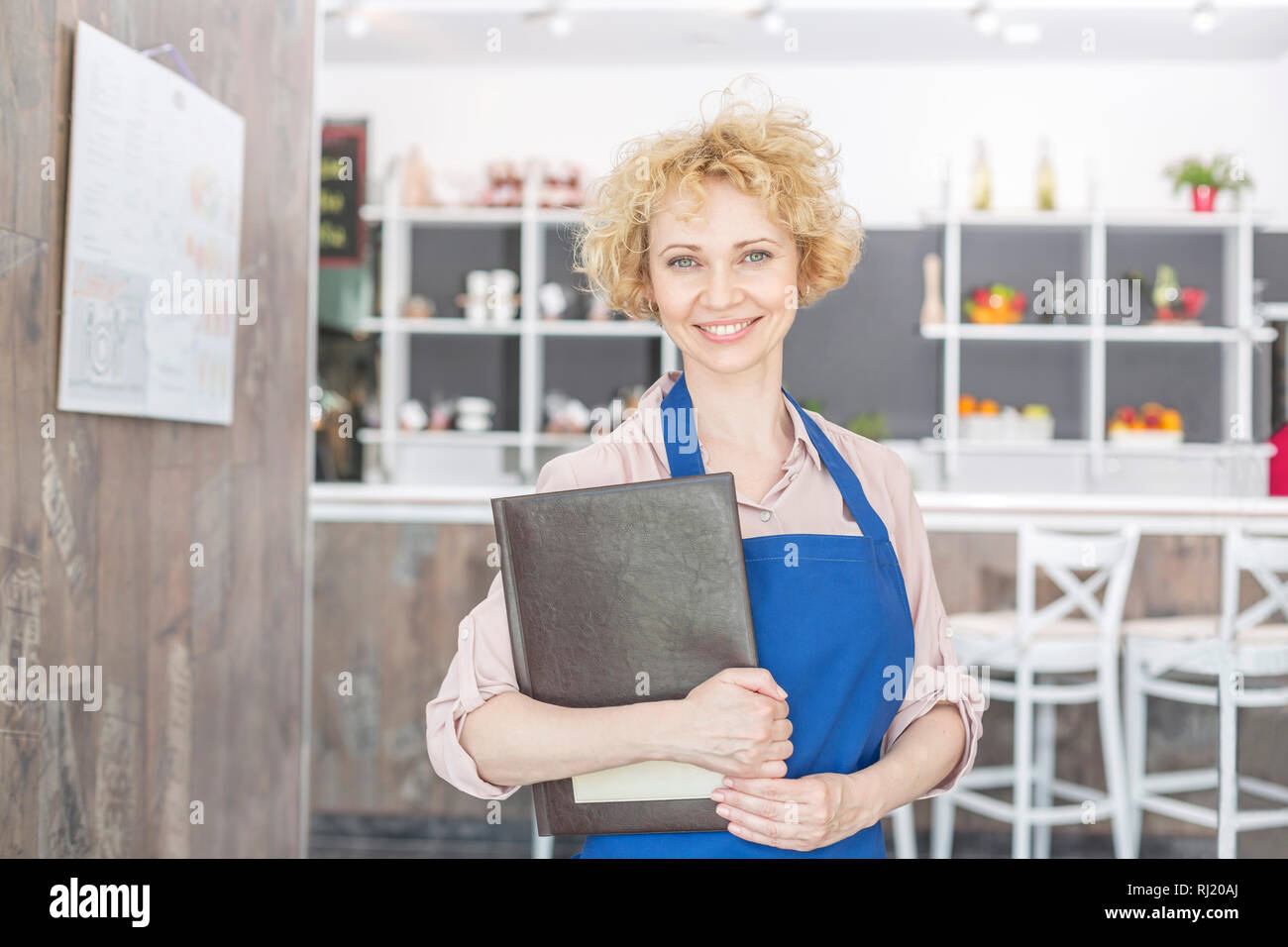 Portrait of smiling mature waitress holding menu at restaurant Stock ...
