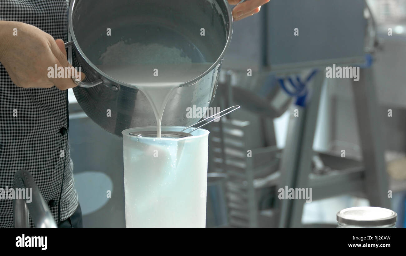 Worker pouring milk into container Stock Photo - Alamy