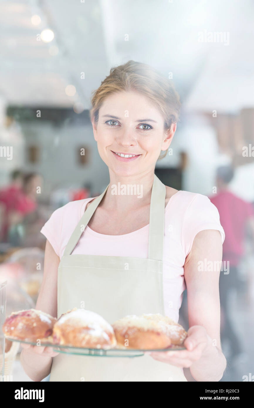 Portrait of smiling beautiful young waitress serving fresh bread at ...