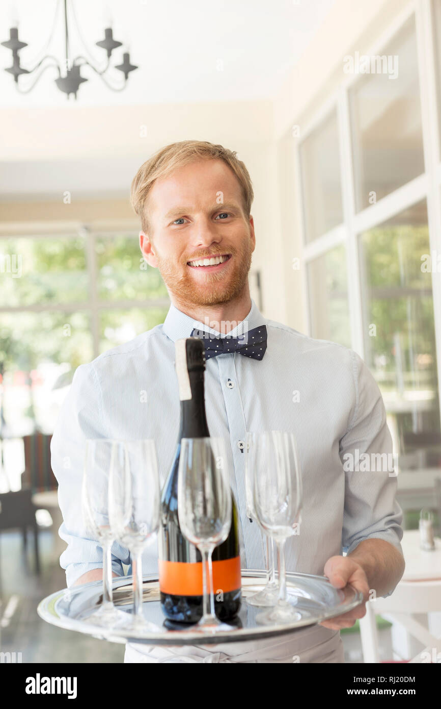 Portrait of confident young waiter serving wine at restaurant Stock ...