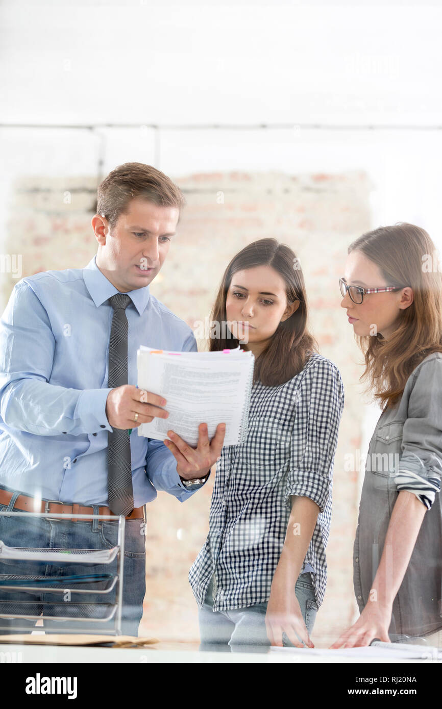 Mid adult businessman showing documents to colleagues in office Stock ...