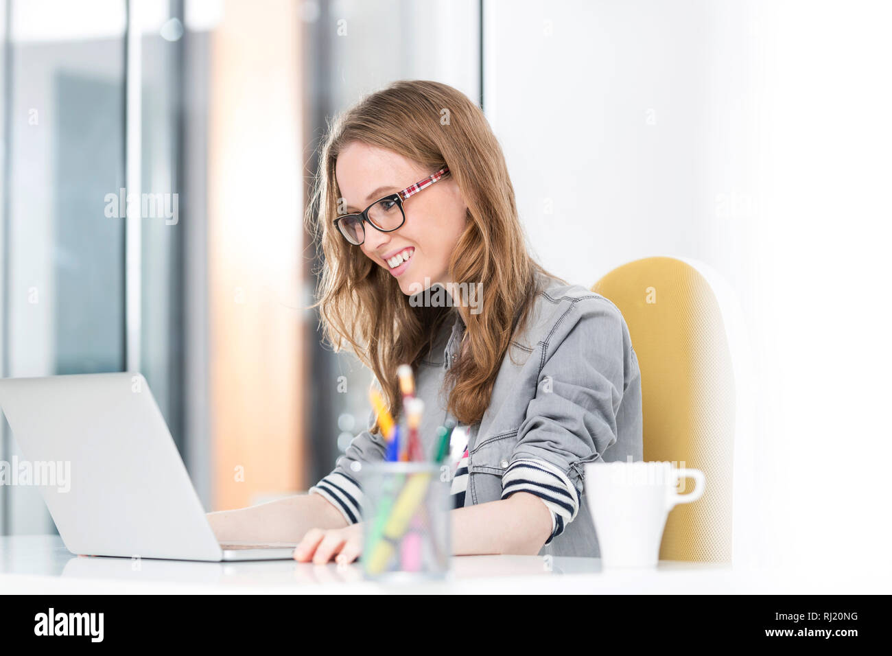 Smiling businesswoman reading an email on laptop in office Stock Photo ...