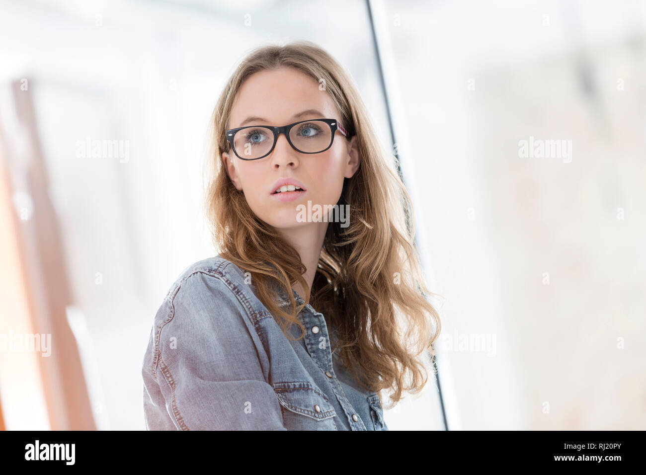 Beautiful young businesswoman wearing eyeglasses while looking away ...