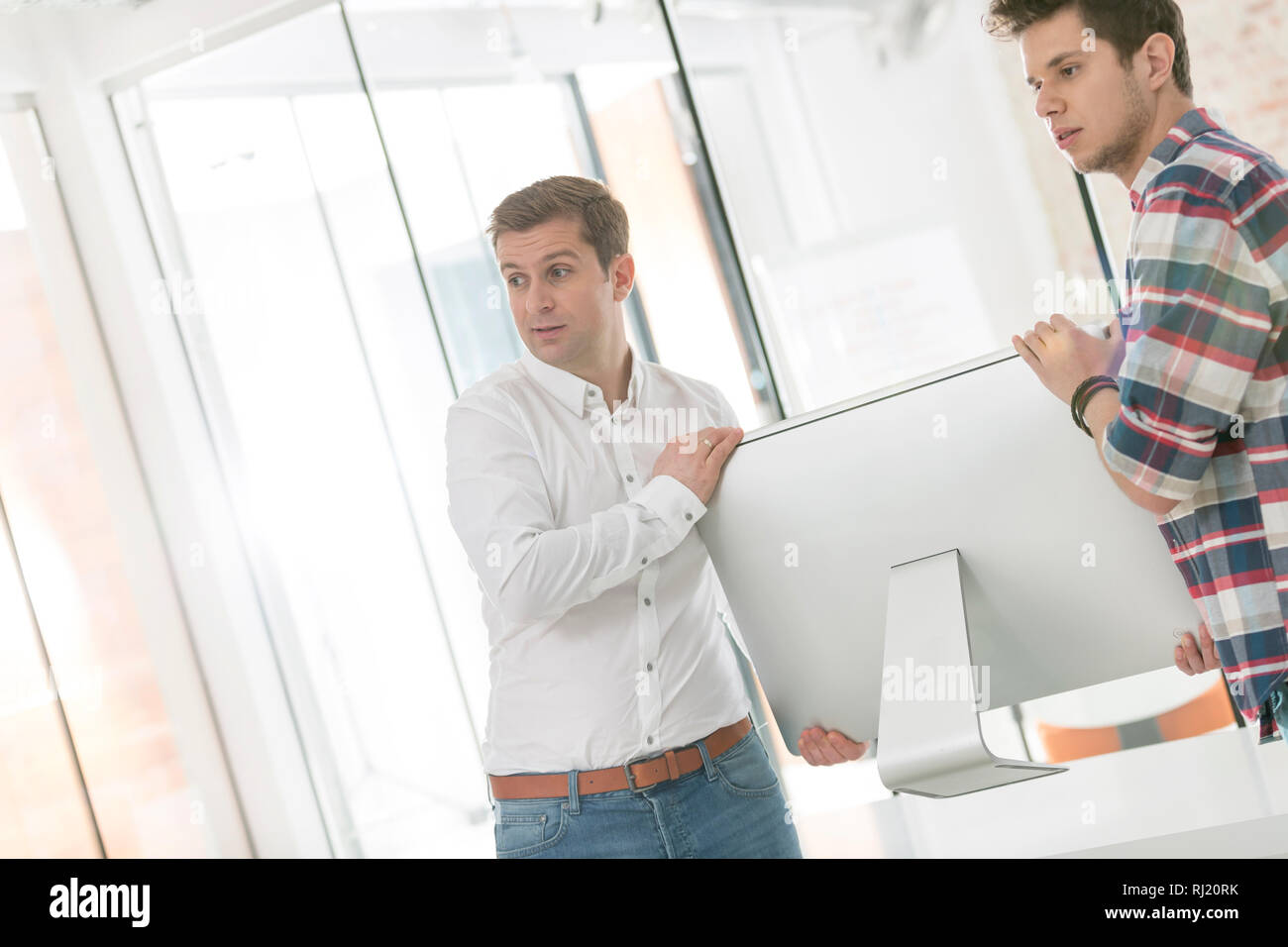 Creative businessmen carrying desktop computer in office Stock Photo ...