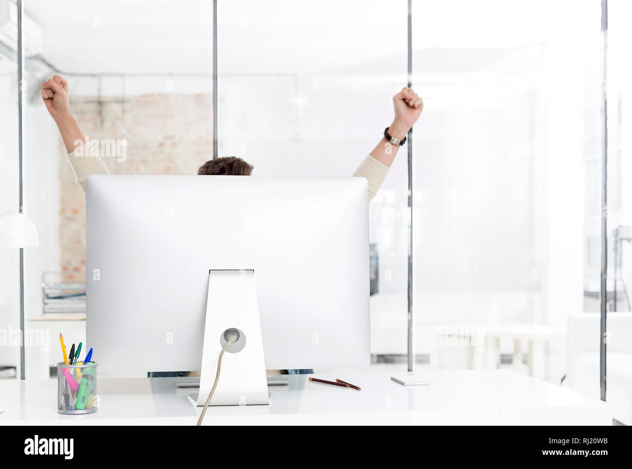 Businessman celebrating victory while raising hands at computer desk ...