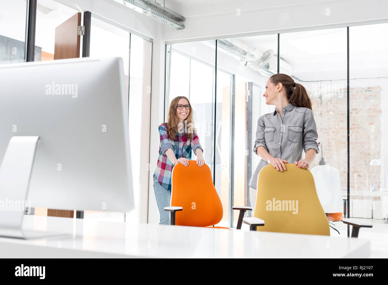 Businesswomen pushing chairs in new office Stock Photo - Alamy