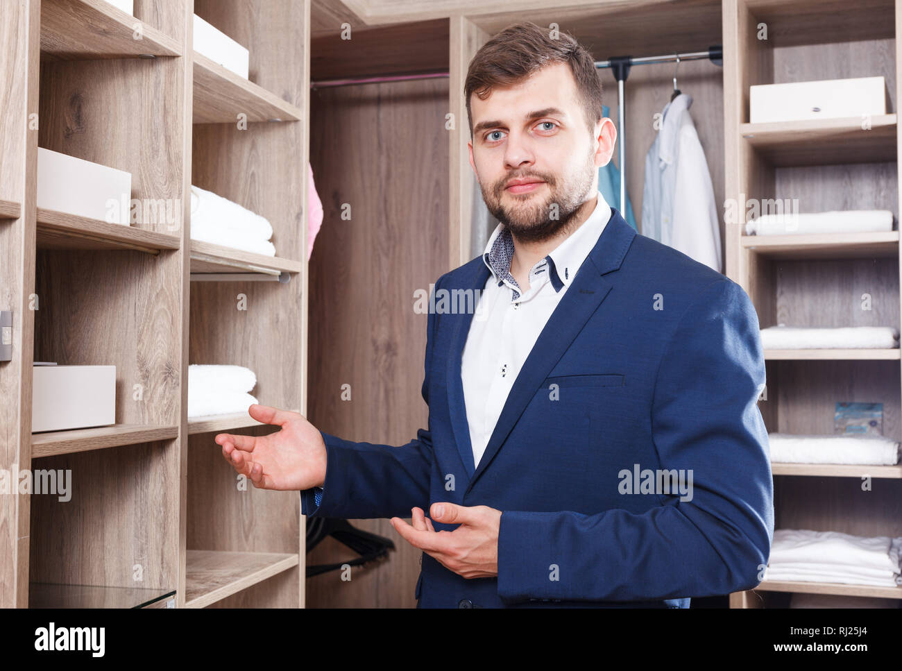 Young successful sales manager demonstrating modern dressing room in ...