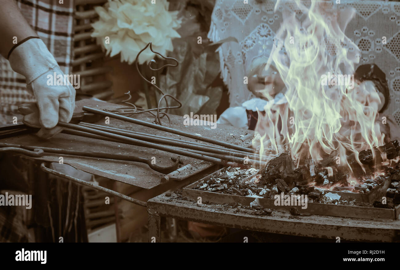 In a small mobile forge at the fair the blacksmith makes forged ...