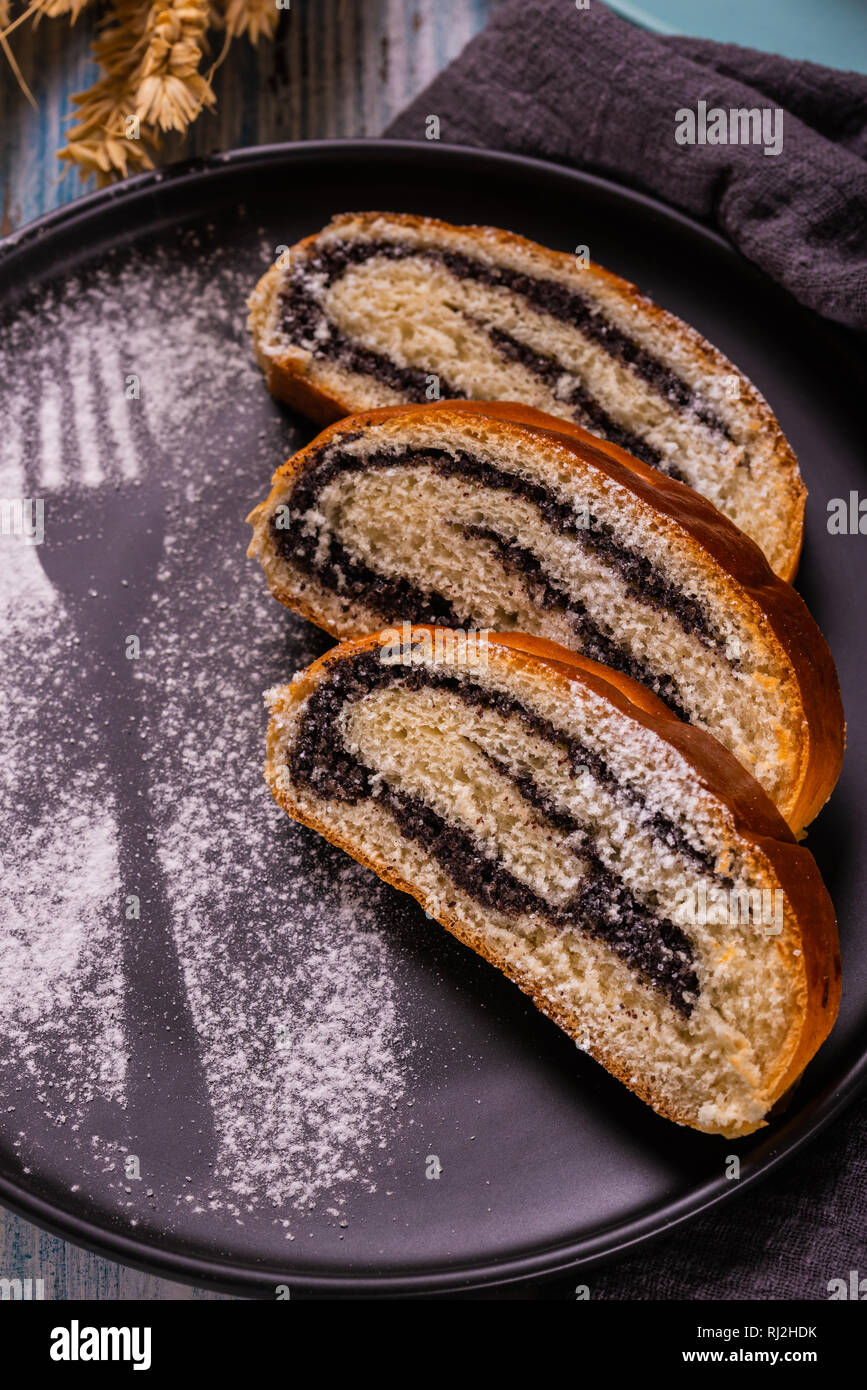 Poppy seed strudel on dark plate with silhouette of fork made by sugar ...