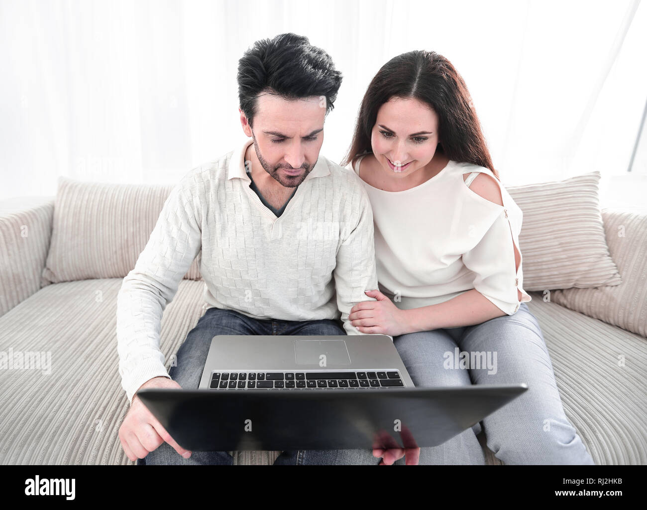 couple with laptop sitting in the living room on the sofa Stock Photo ...