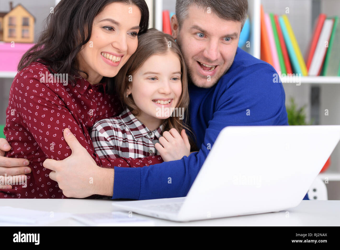 parents and daughter using laptop in room Stock Photo - Alamy