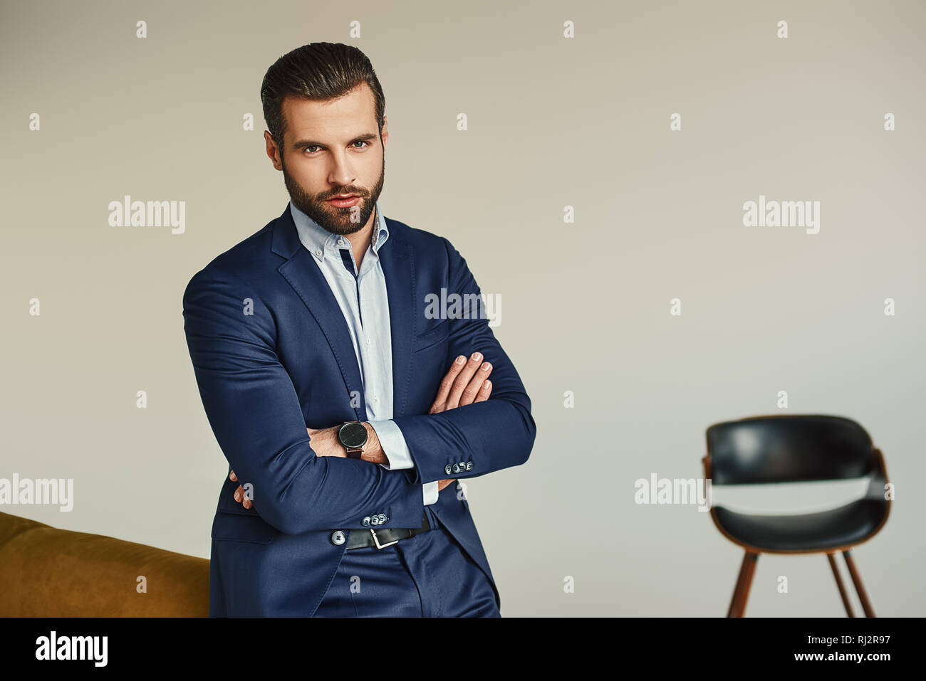 Portrait of a charming young businessman dressed in suit posing while ...
