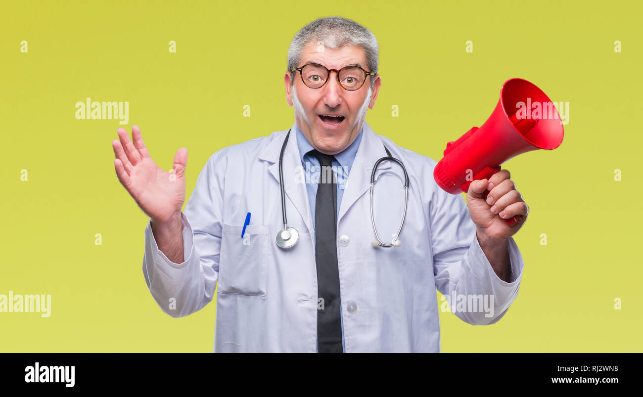 Handsome senior doctor man yelling through megaphone over isolated ...