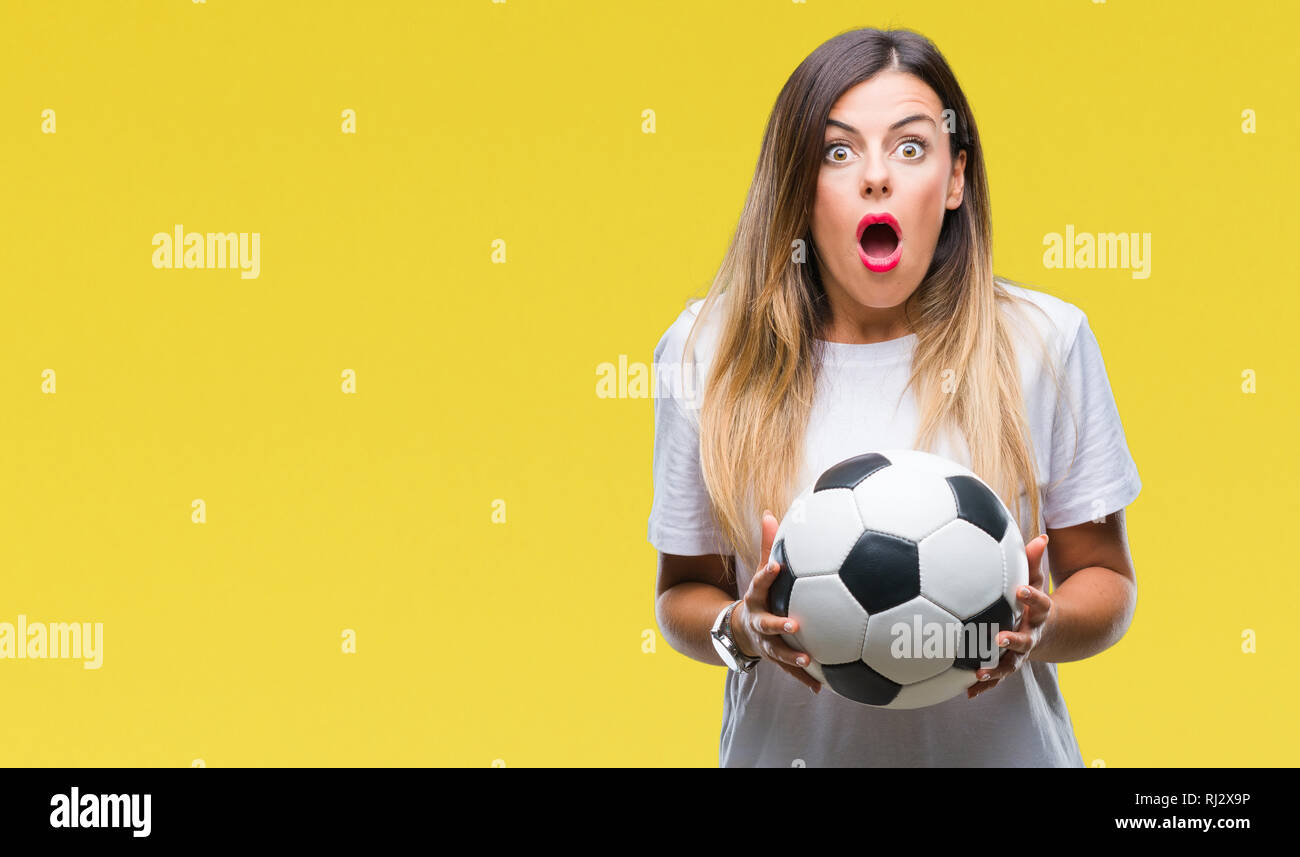 Young beautiful woman holding soccer ball over isolated background ...
