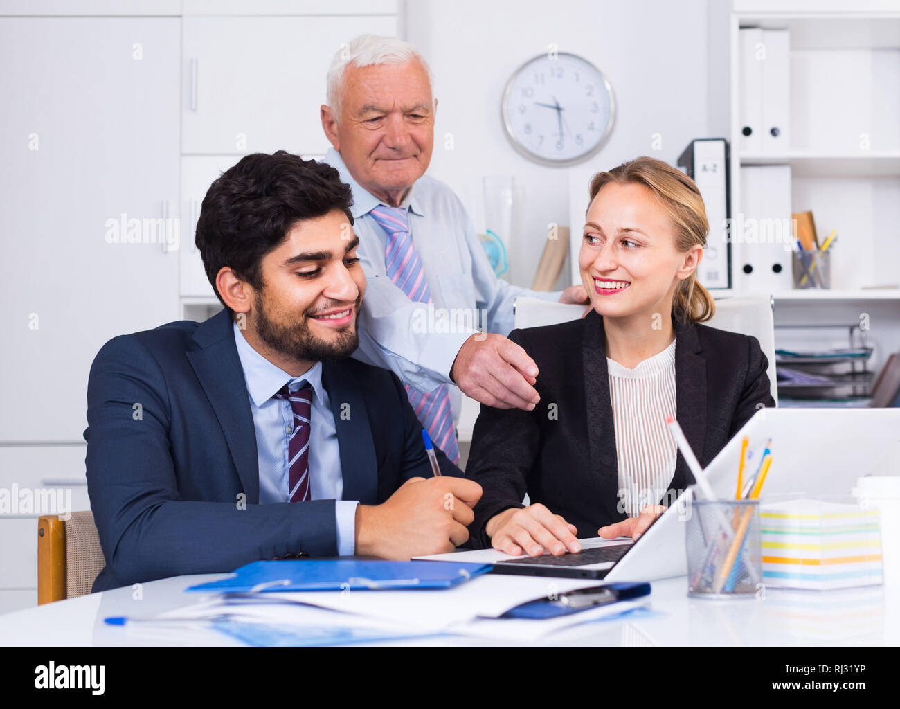 Employees are demonstrating reports on laptop to mature boss in the ...