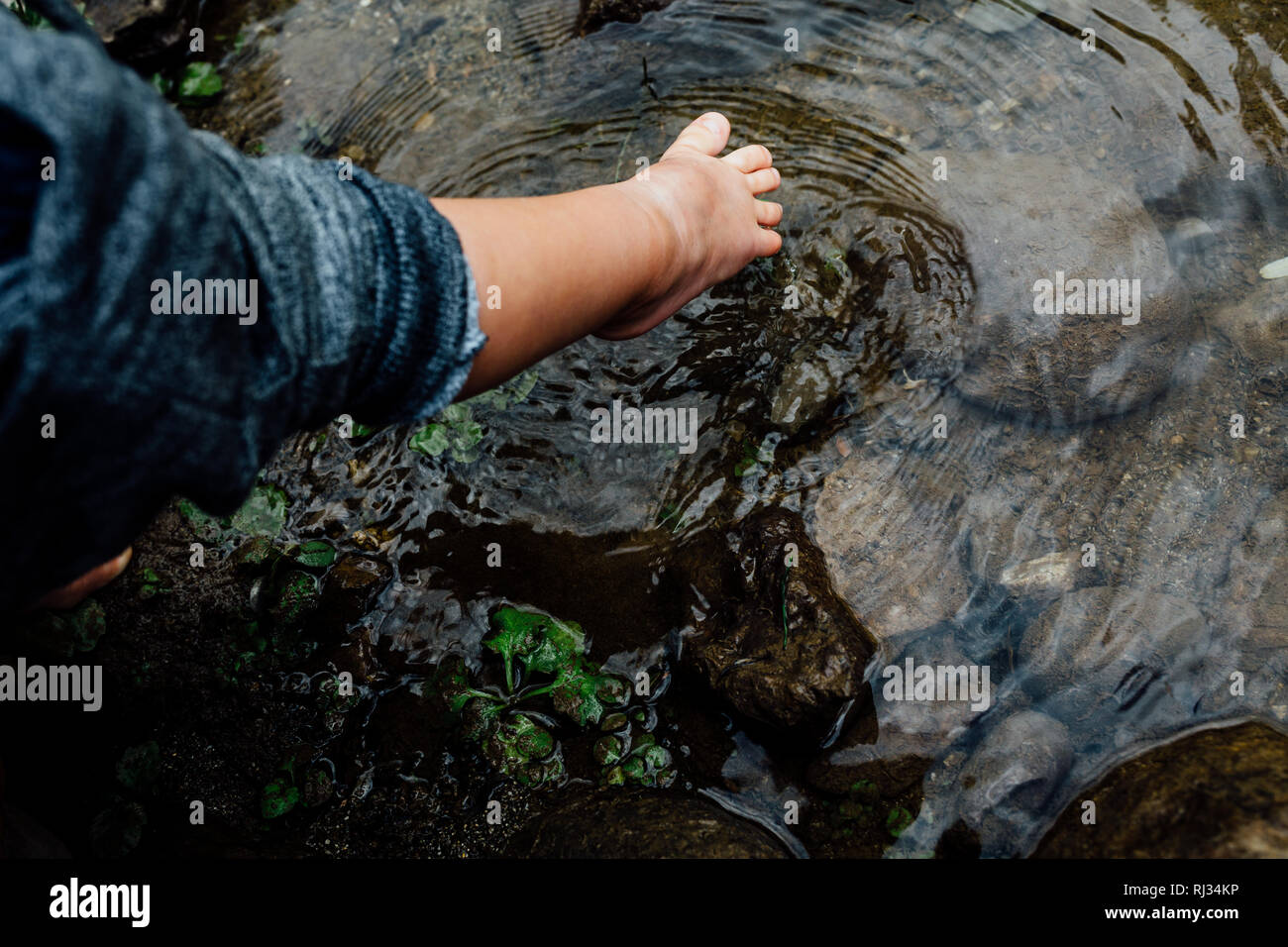 Children feet is touching water creating ripples. Sign of happiness ...