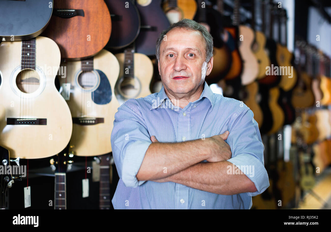 Adult glad cheerful positive smiling guitarist is standing with ...