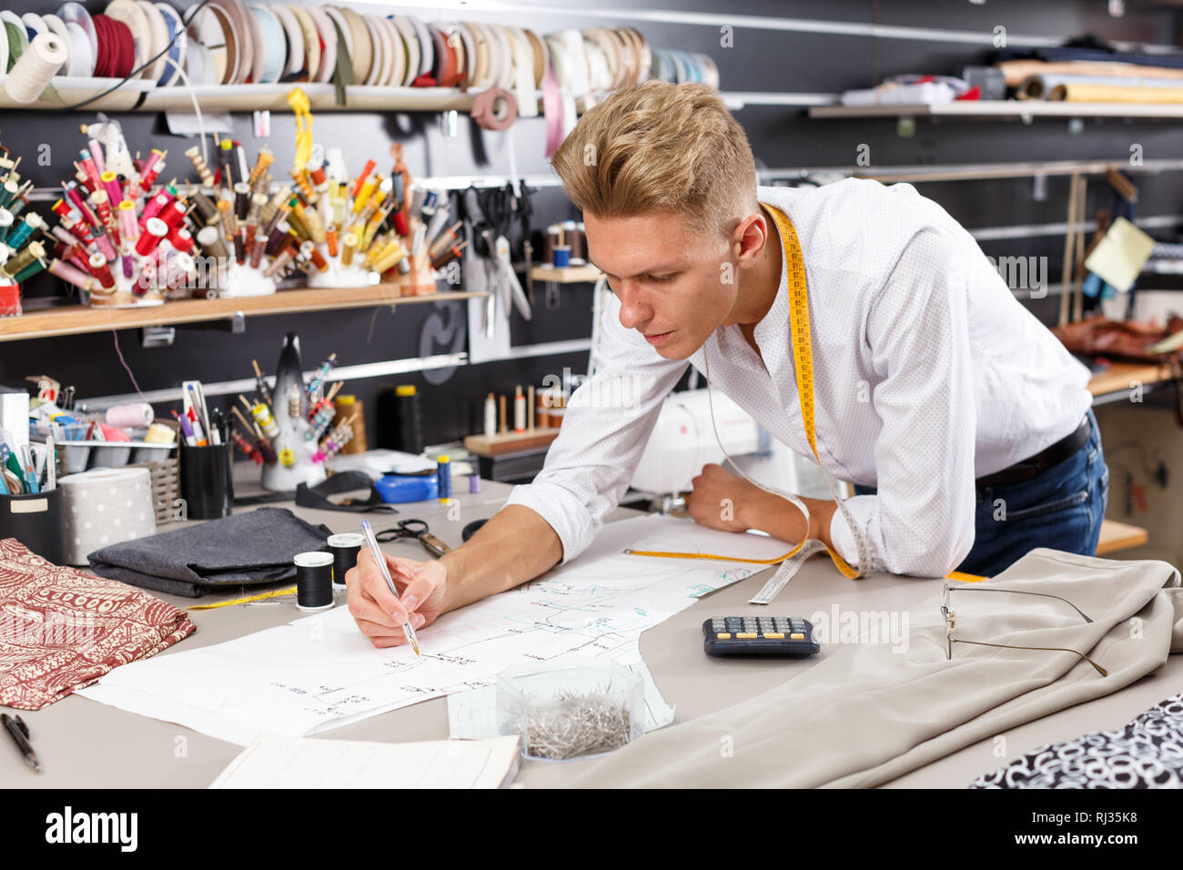 Professional male dressmaker at work – creating pattern at his ...