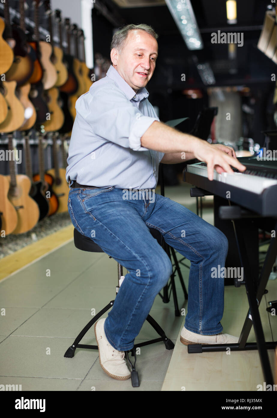 Smiling musician is playing on modern keyboard in music shop Stock ...